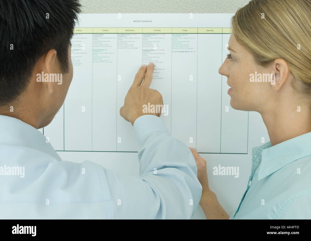 Two colleagues looking at chart on wall Stock Photo - Alamy