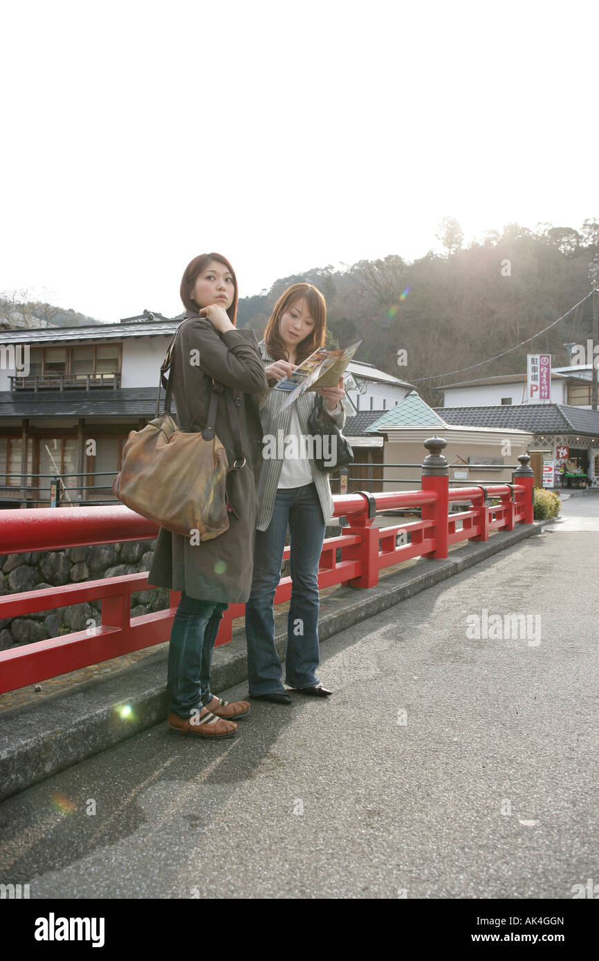 Two young women referring to guide book Stock Photo - Alamy