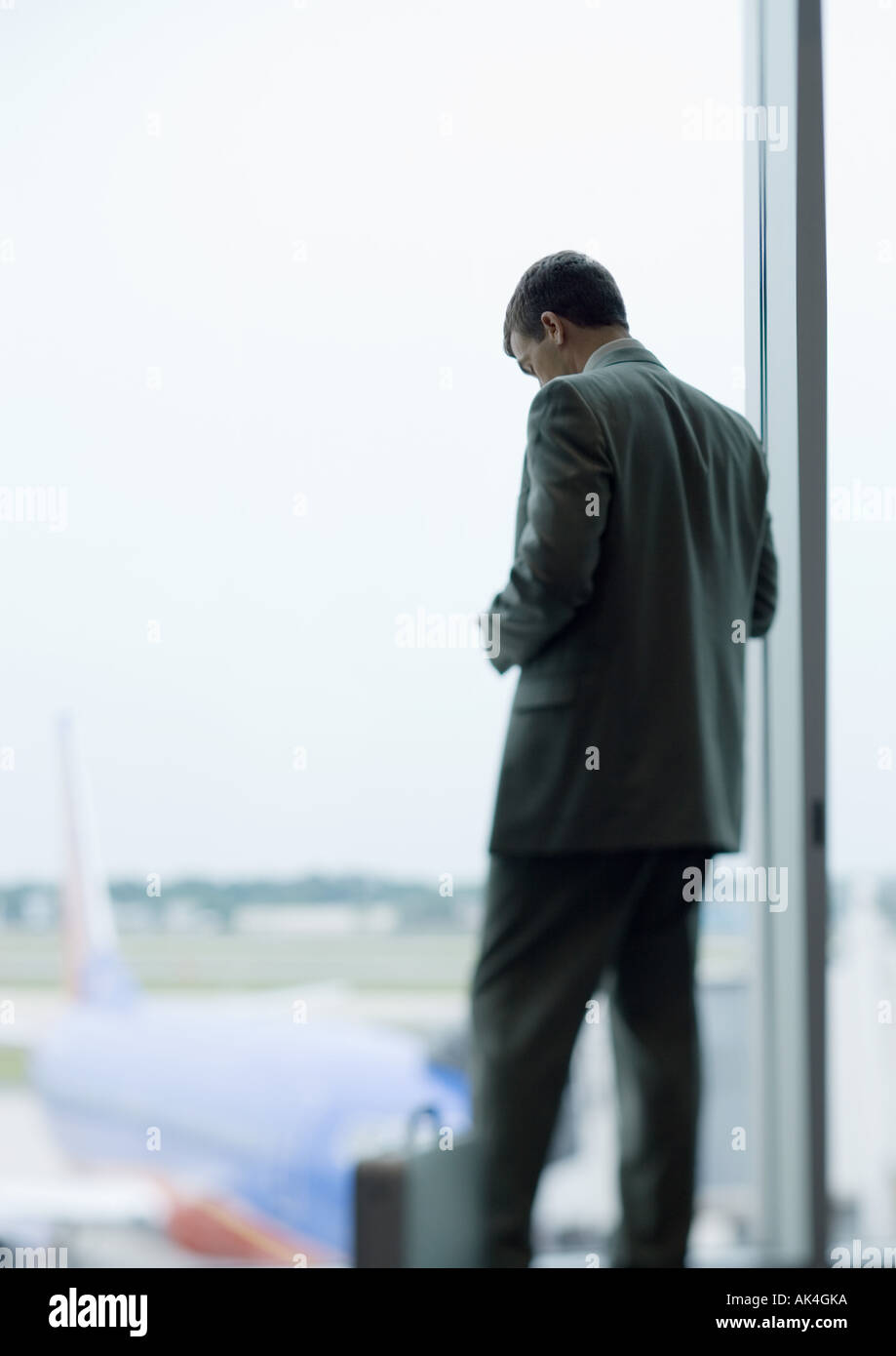 Man standing looking down, airplane in background Stock Photo - Alamy
