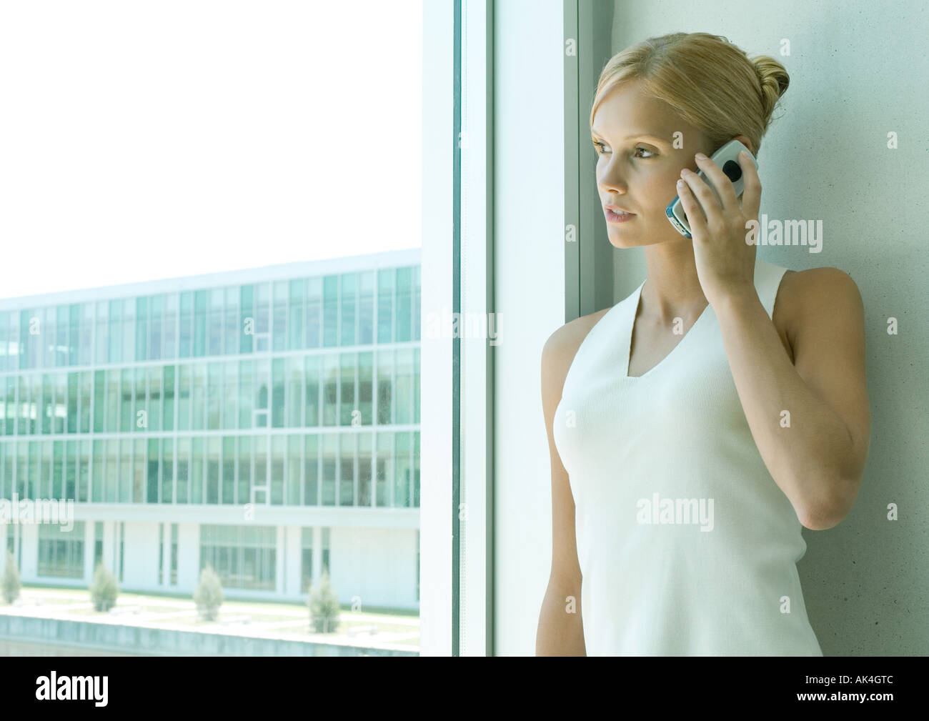 Woman leaning against wall using cell phone hi-res stock photography ...