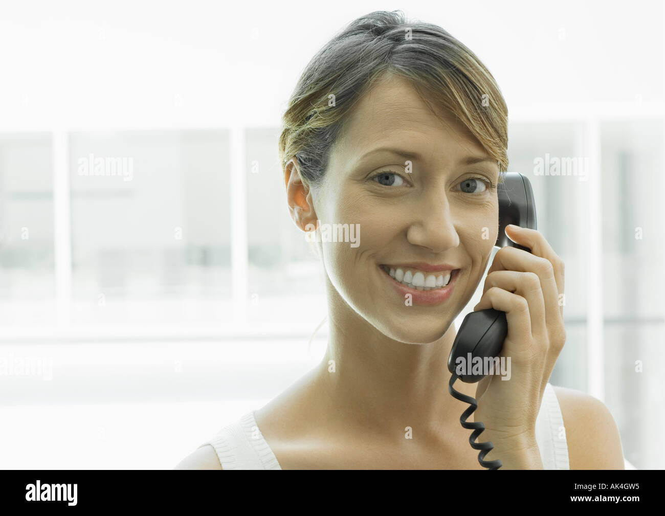 Woman using landline phone, smiling at camera Stock Photo - Alamy