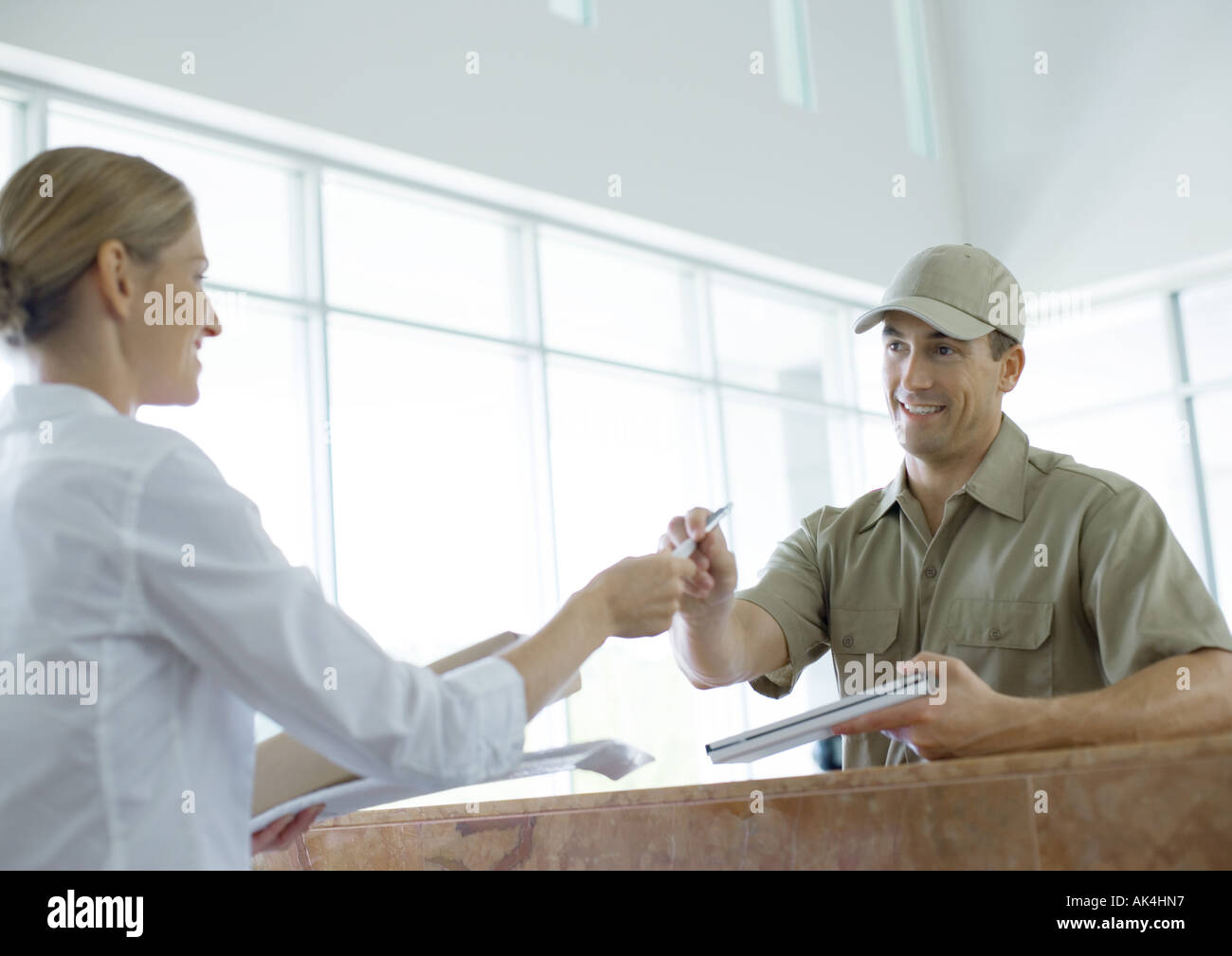 Receptionist handing pen to delivery man Stock Photo - Alamy