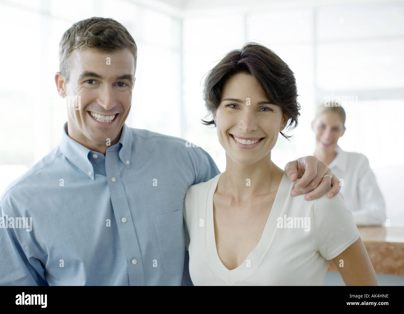 Couple smiling, reception desk in background Stock Photo - Alamy