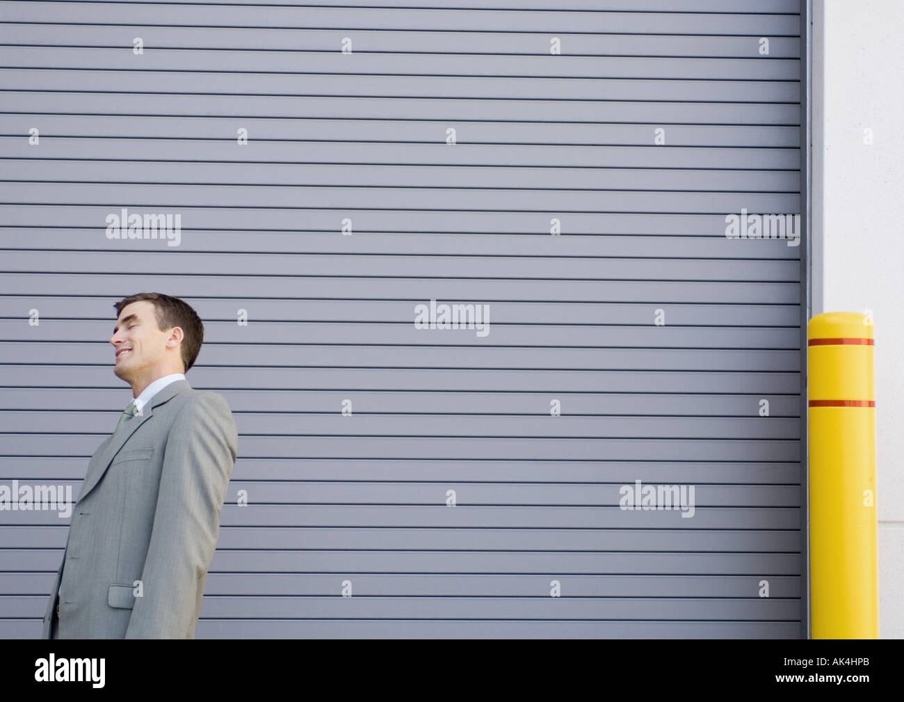 Businessman standing and smiling, leaning backwards with eyes shut ...