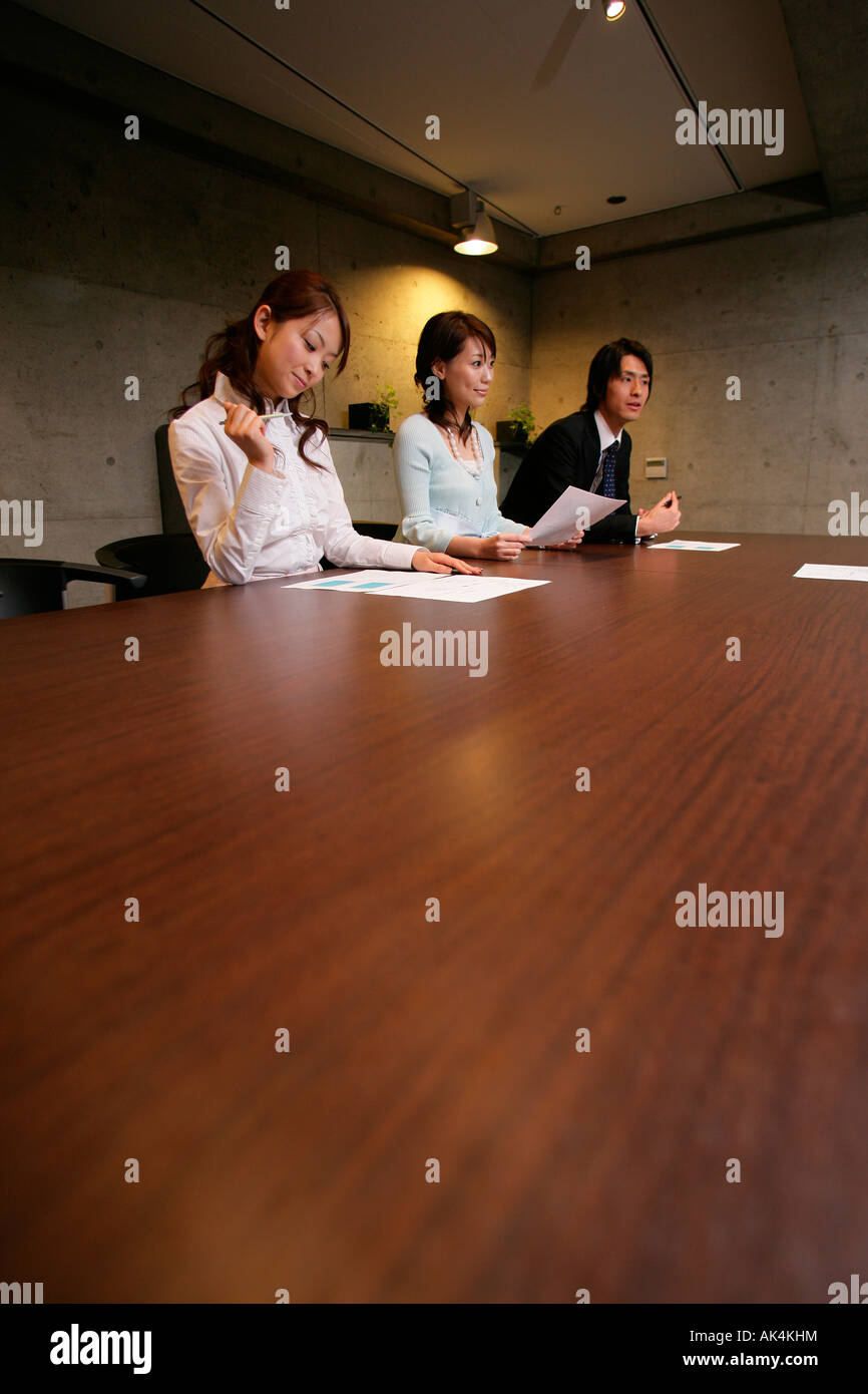 Businessman and two women sitting at conference table Stock Photo - Alamy