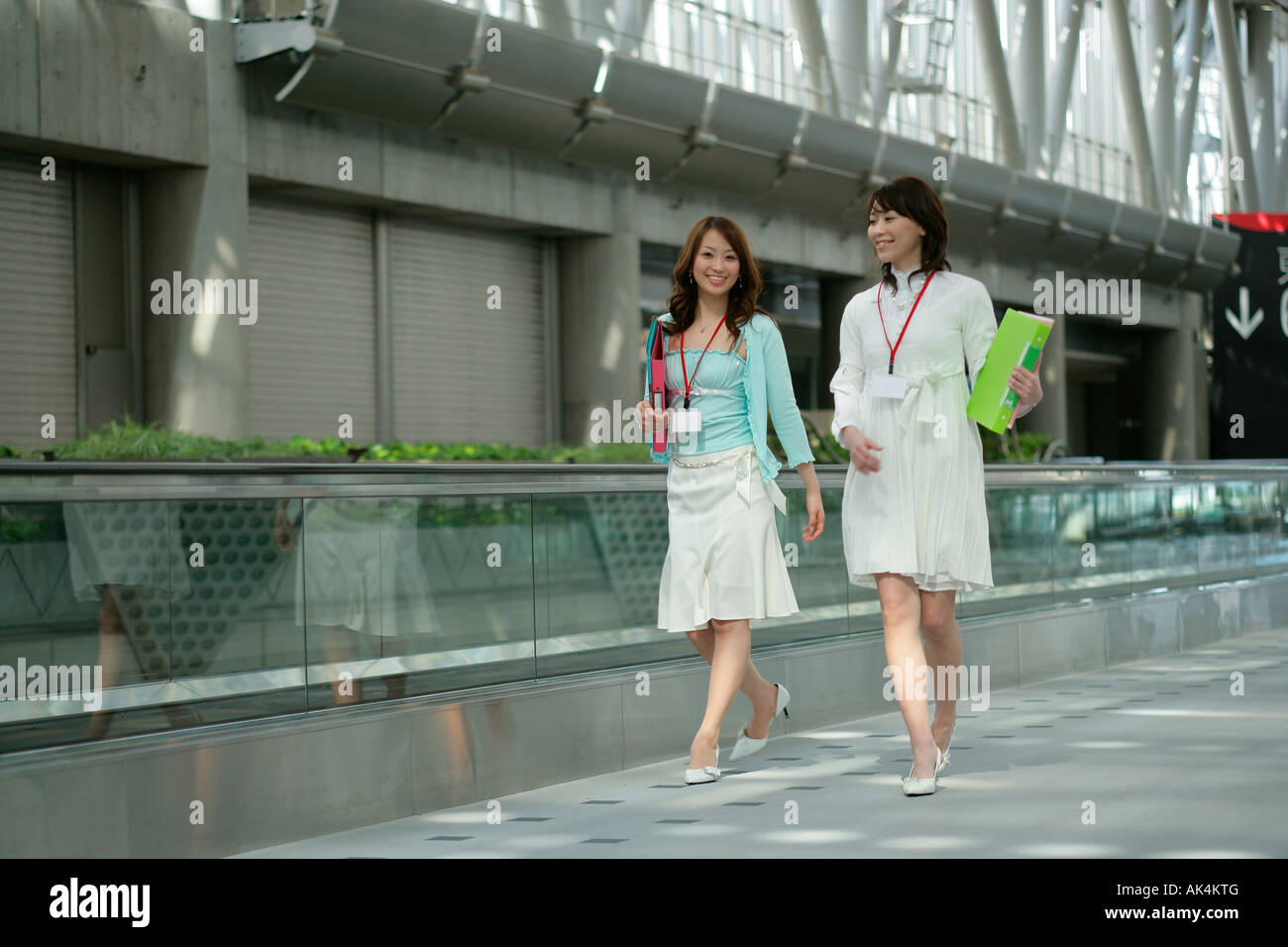 Two women carrying files, walking Stock Photo - Alamy
