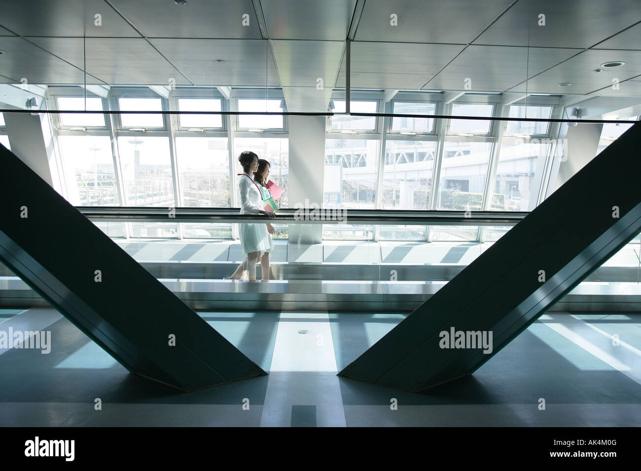 Two women walking in a building Stock Photo - Alamy