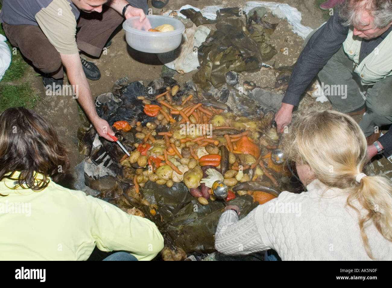 opening the pit oven at a curanto cooking in a pit oven vegetables and ...