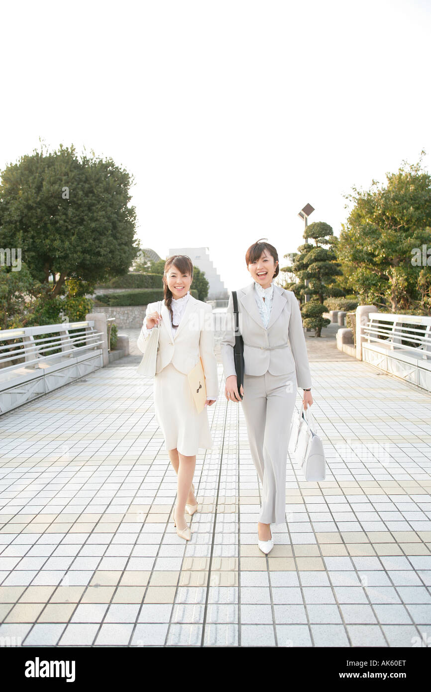Two female office workers walking along walkway Stock Photo - Alamy