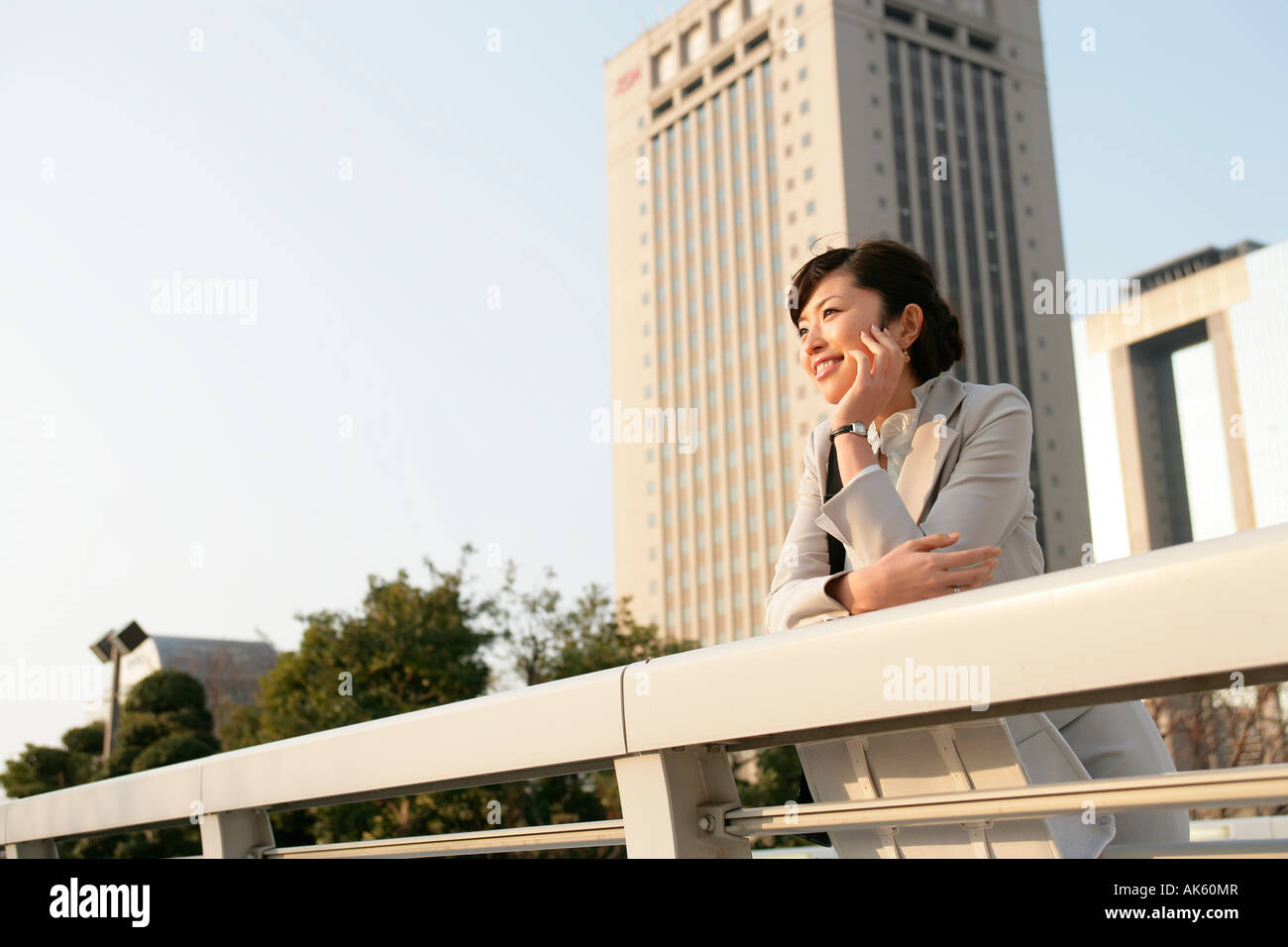 Woman leaning against railing Stock Photo - Alamy