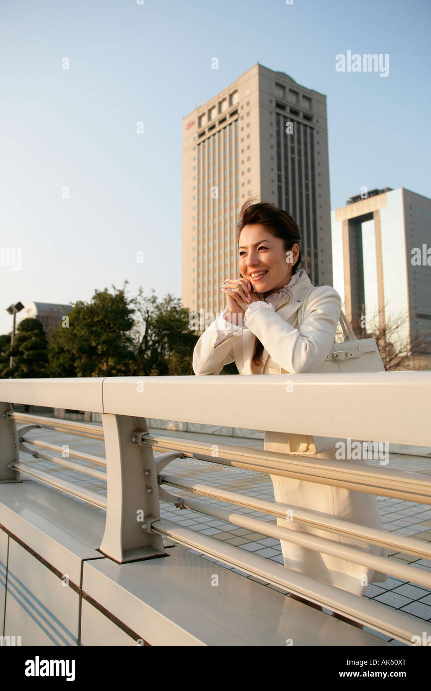 Woman leaning against railing Stock Photo - Alamy