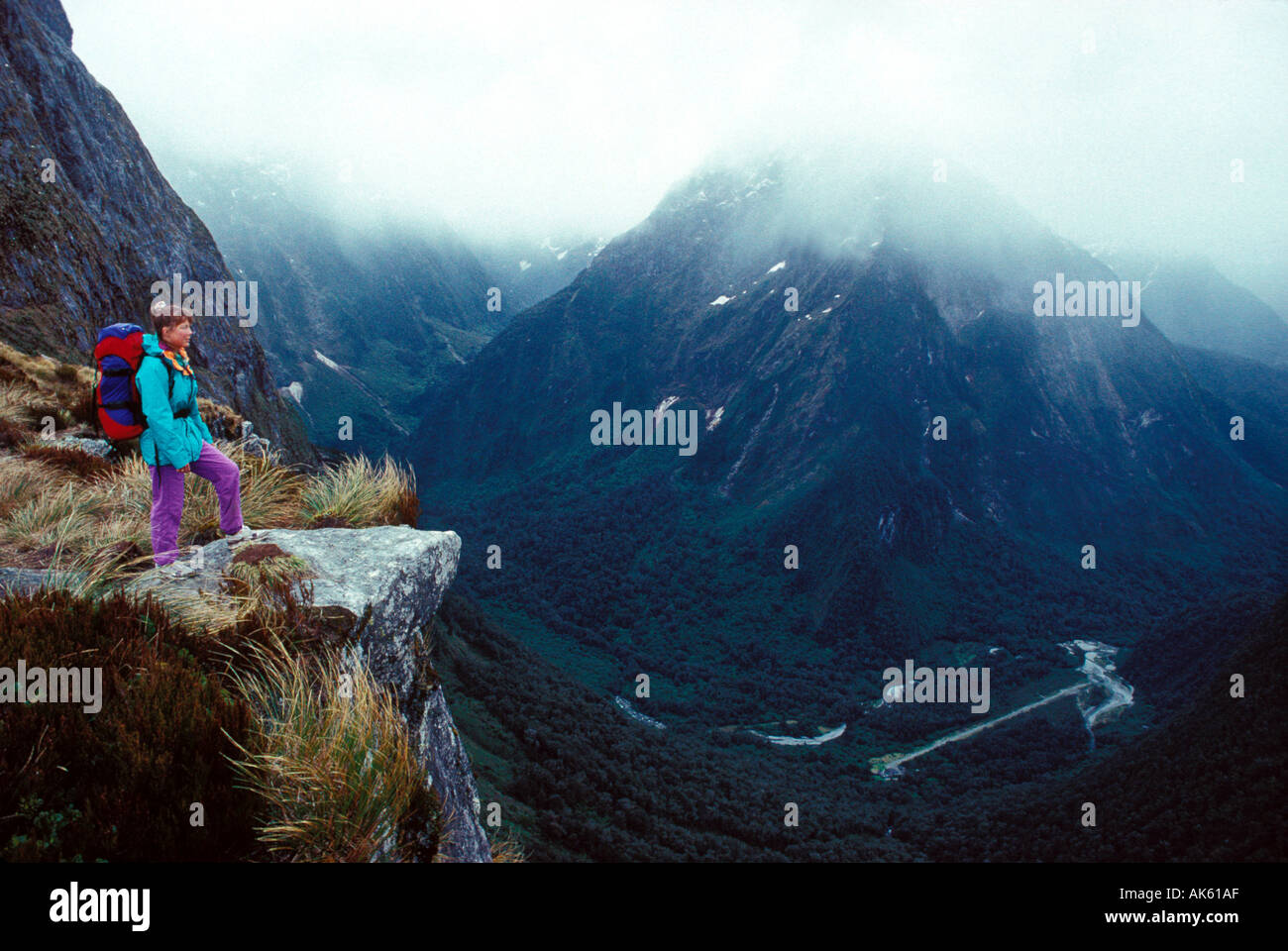 Female walker on a ledge looking at the view at Milford Track New ...