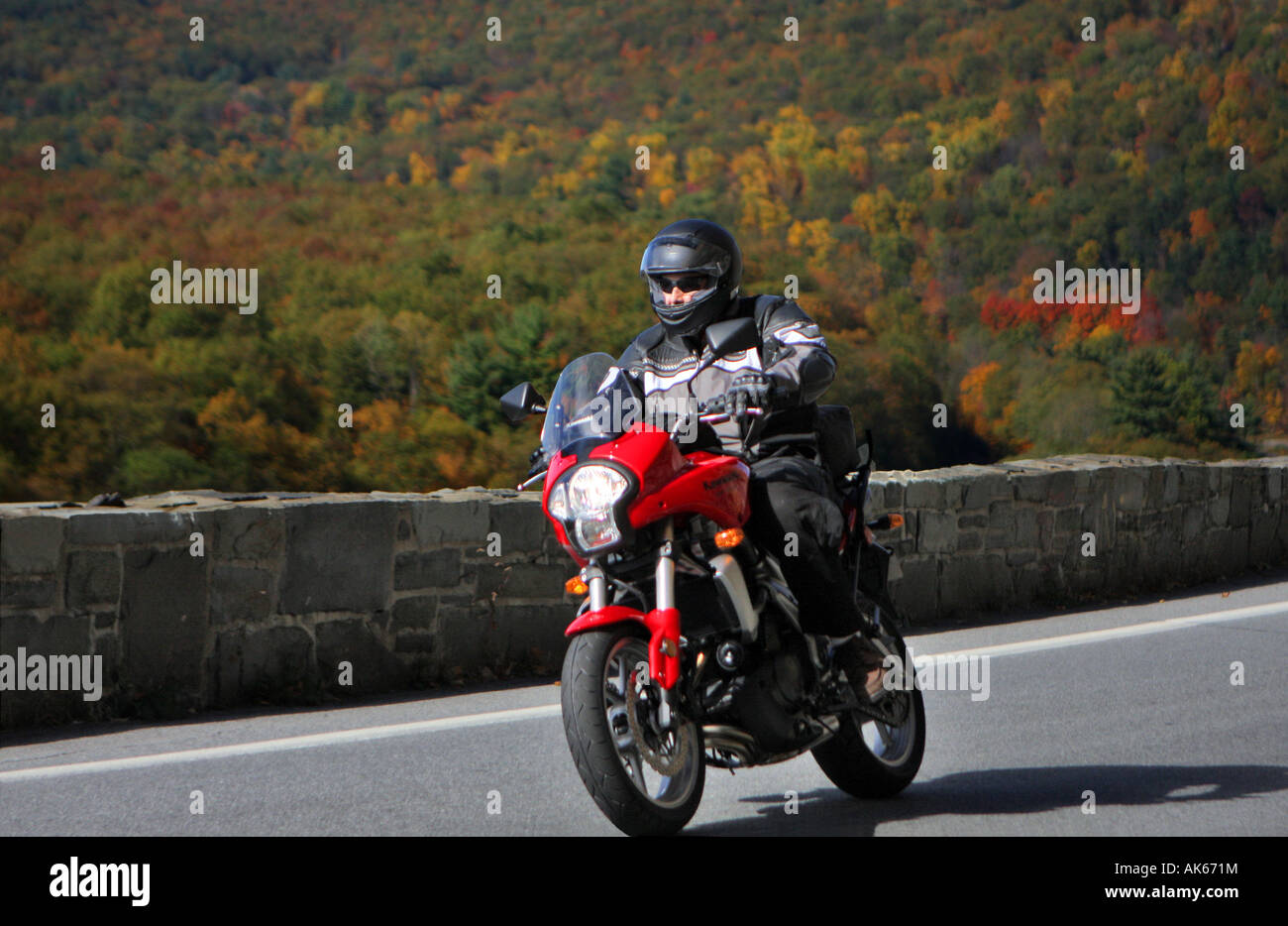 A brand new red dual sport motorcycle on a mountain road. A stone wall ...