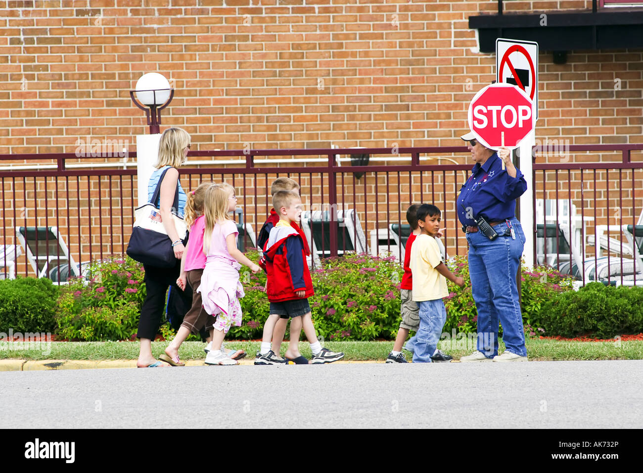 Children walking across the road whilst the traffic is stopped by a ...