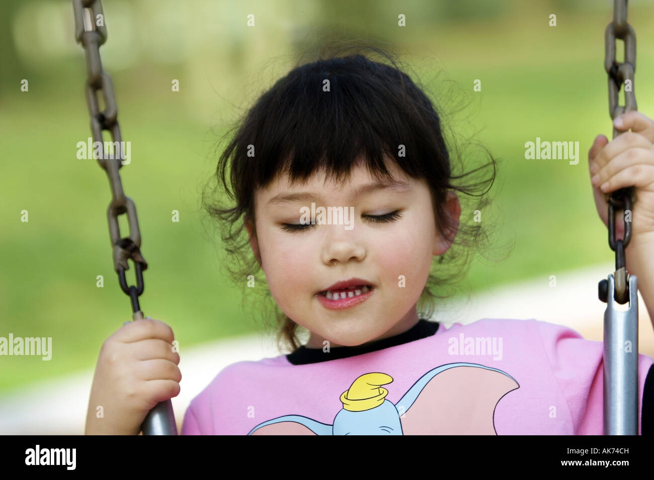 Cute little girl swinging Stock Photo - Alamy