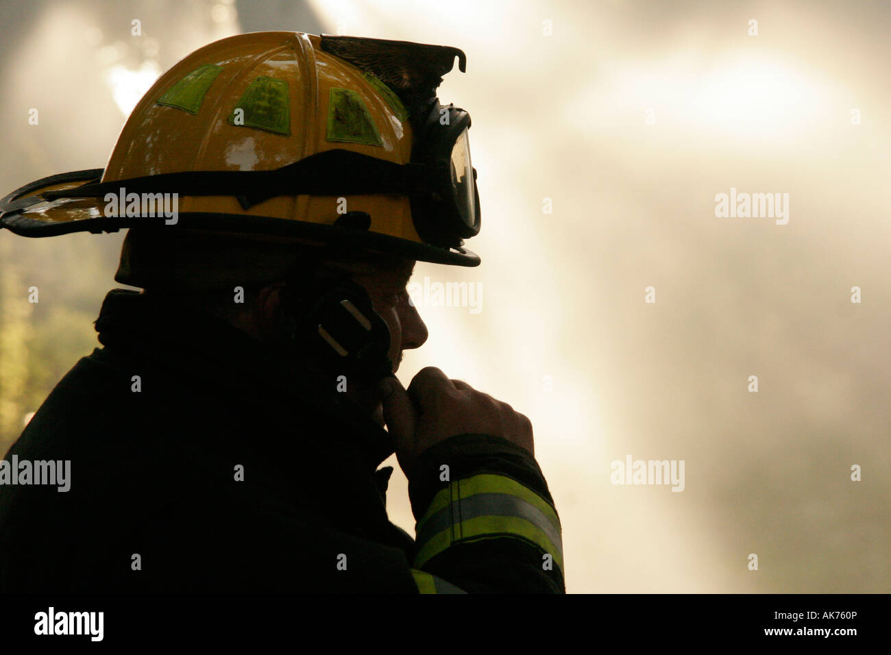 A fire fighter with a yellow helmet listening to the radio on his ear ...