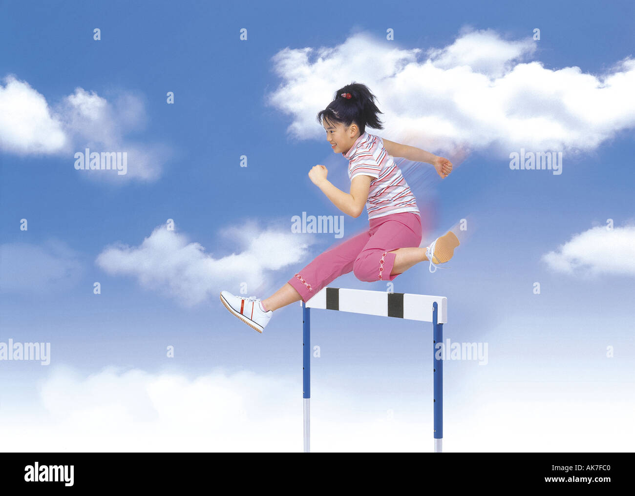 Girl jumping over hurdle Stock Photo - Alamy