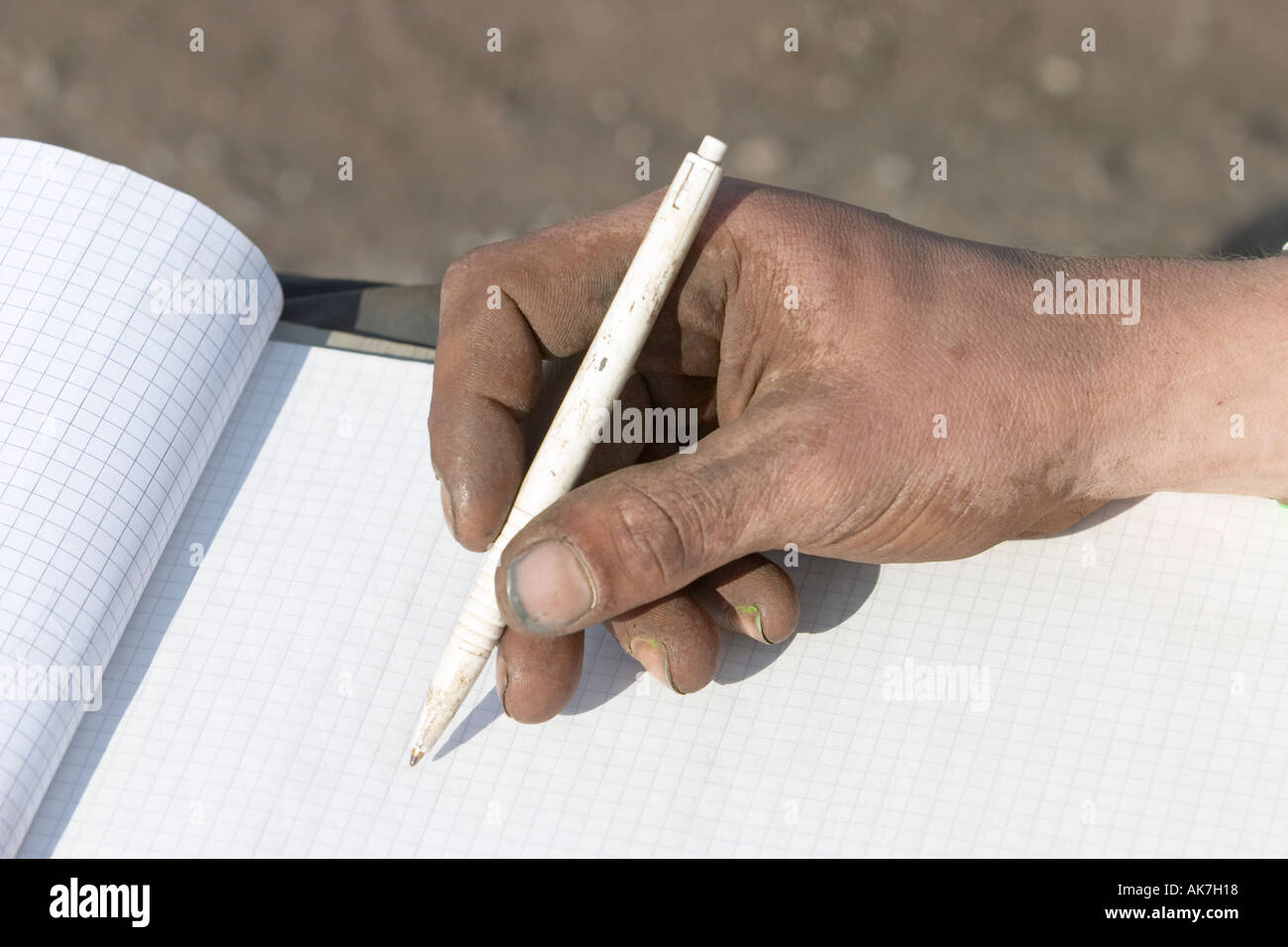 dirty hand holds pen and writes on checkered pad Stock Photo - Alamy