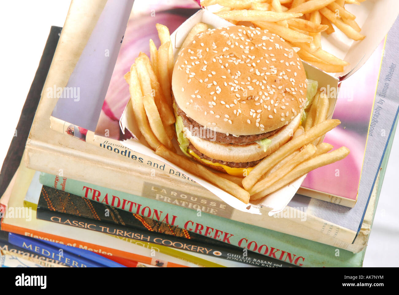 Concept shot to show unhealthy fast food meal on top of pile of cookery ...