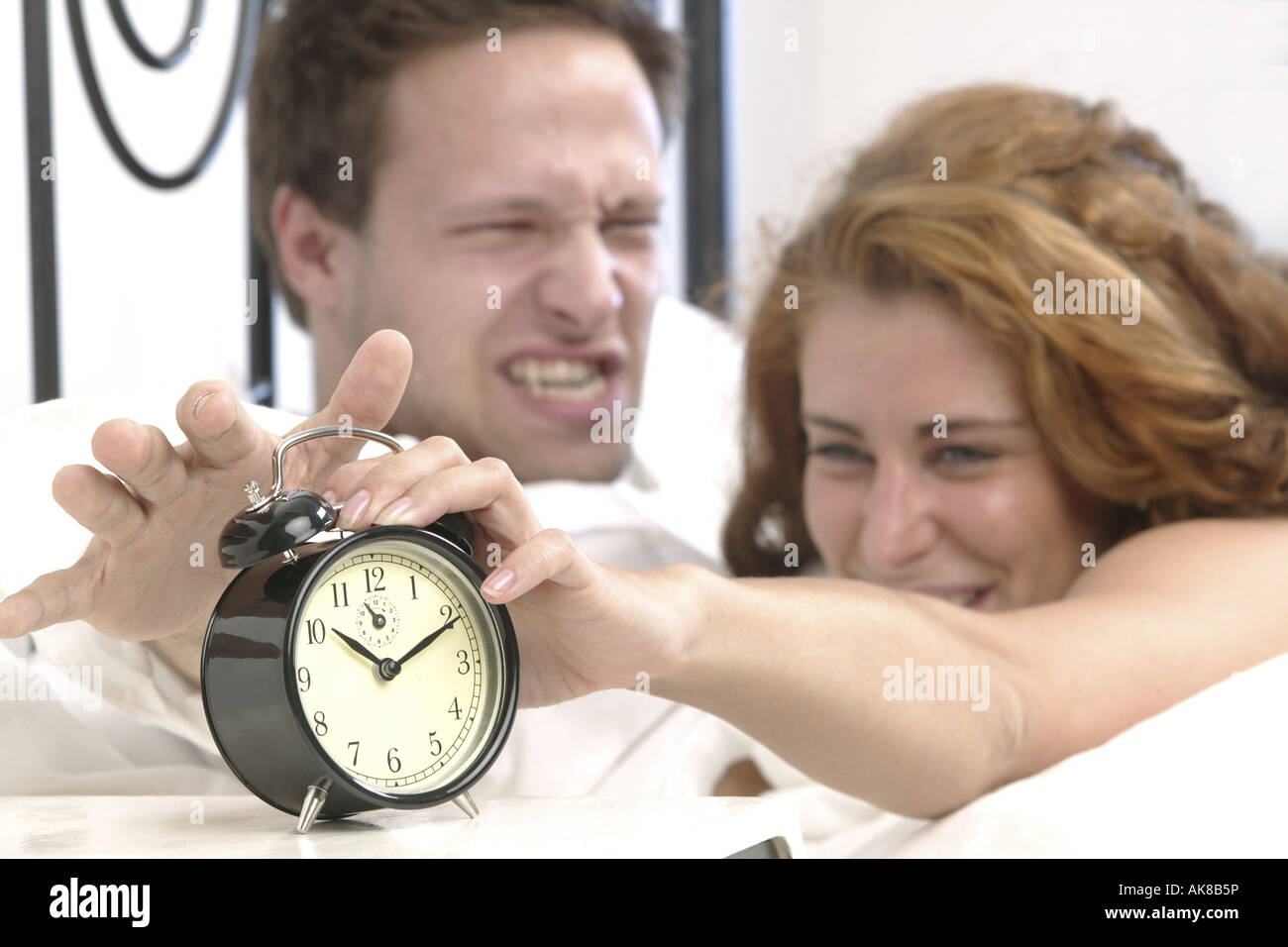alarm clock waking young couple up Stock Photo - Alamy