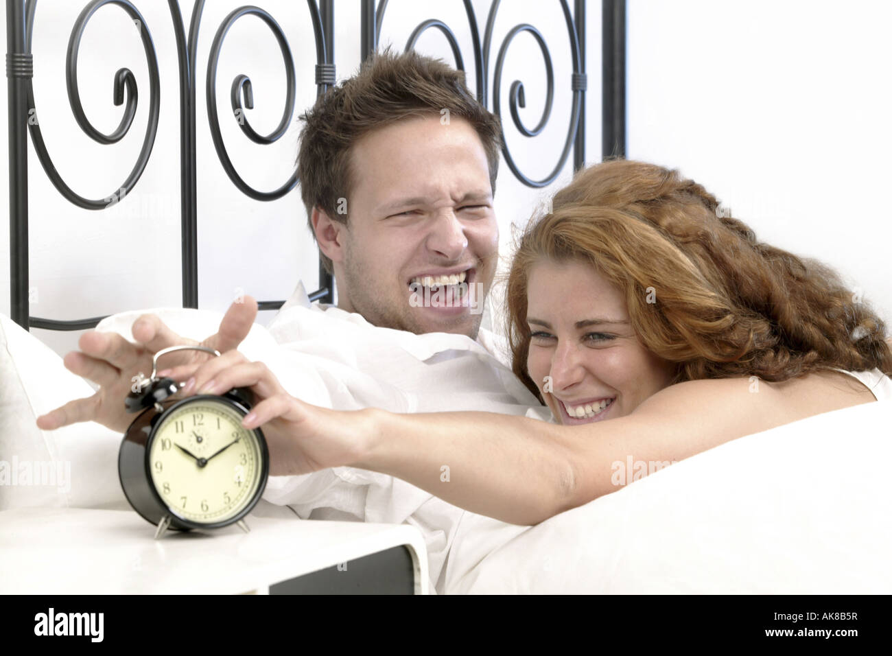 alarm clock waking young couple up Stock Photo - Alamy
