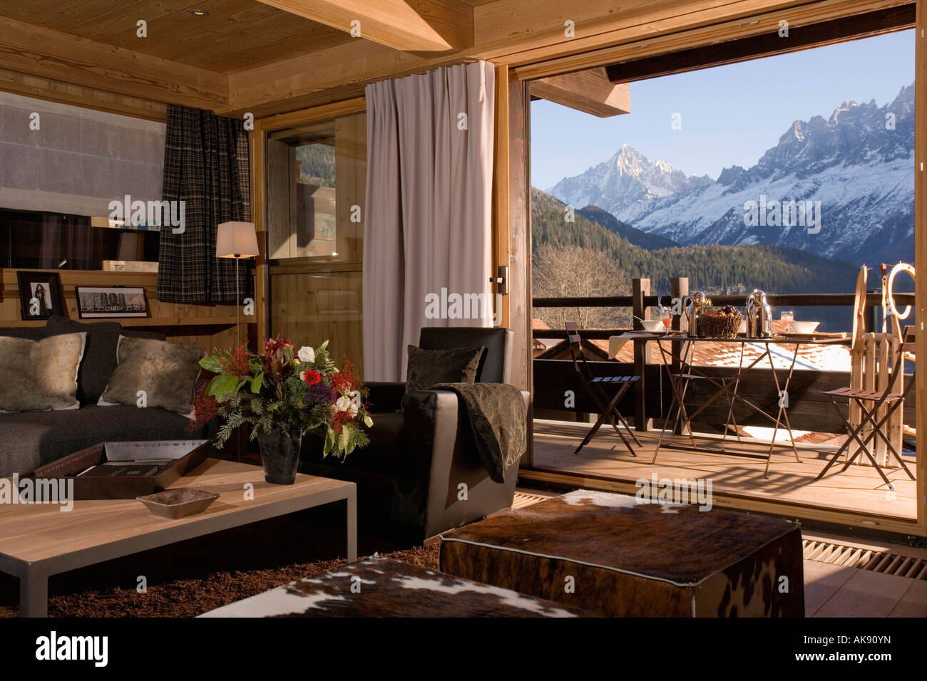 Modern Alpine chalet living room with view through open door of balcony ...