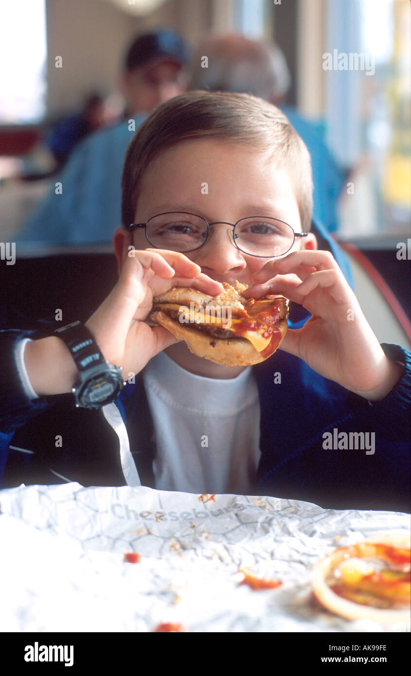Young boy eating a cheeseburger Stock Photo - Alamy