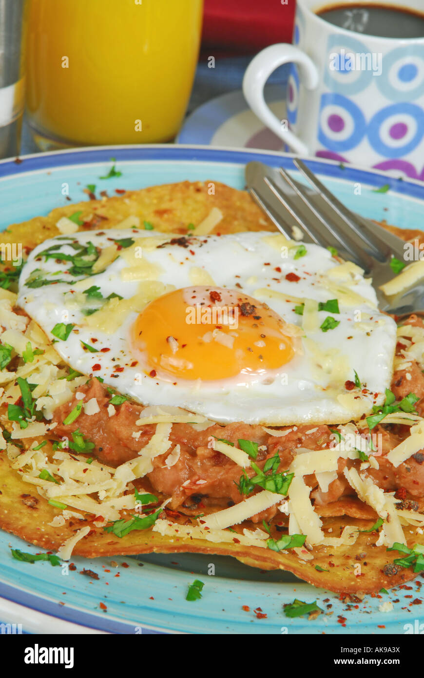 A Mexican-style breakfast of huevos rancheros: fried egg, refried beans ...