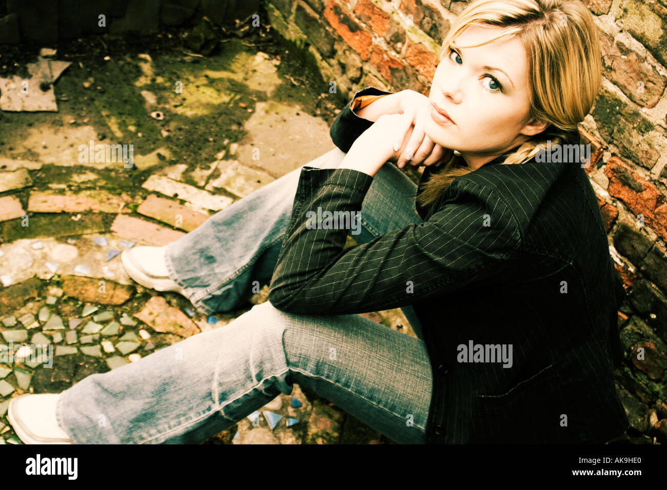 Girl sat outside by wall Stock Photo - Alamy