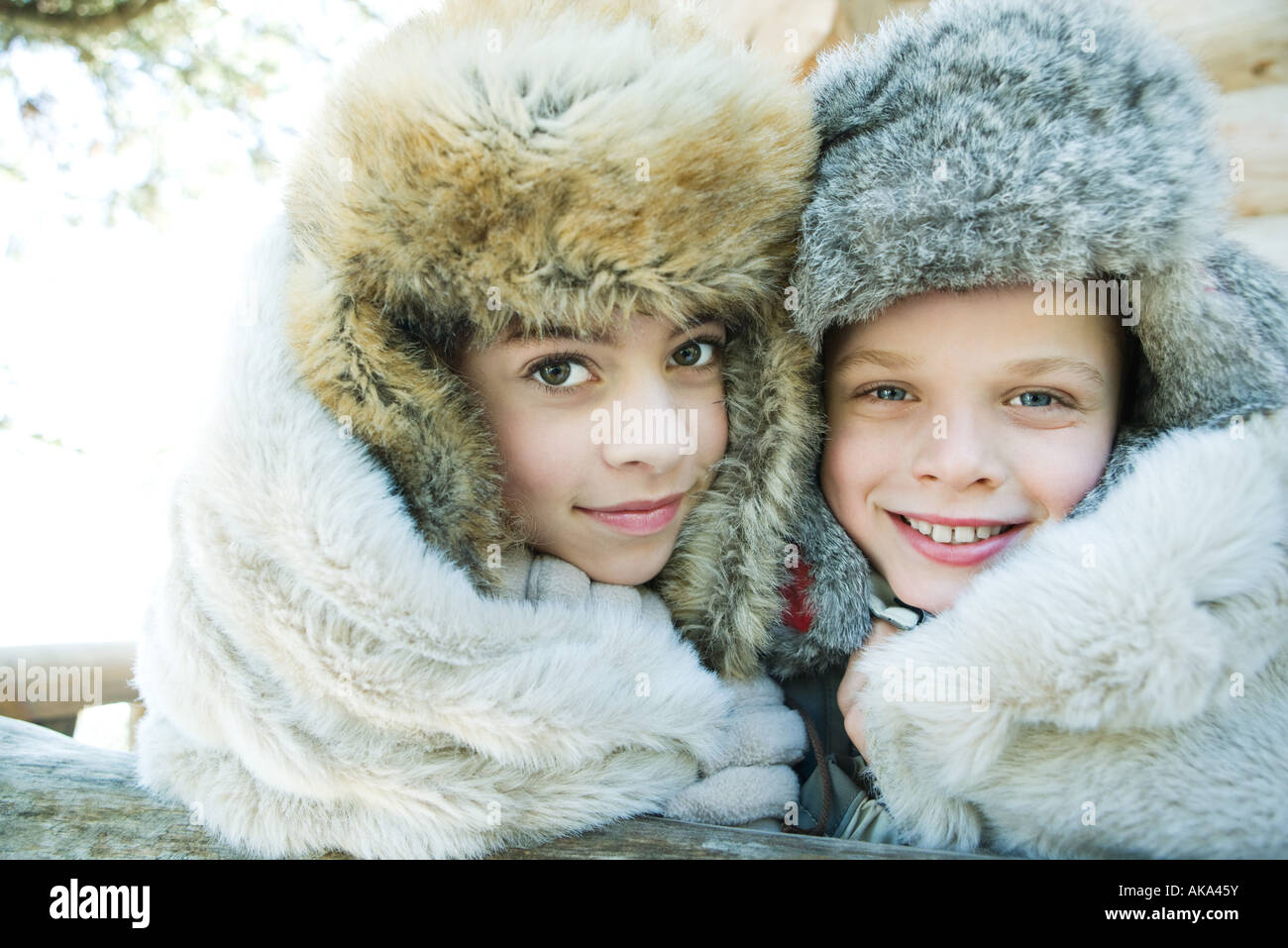 Brother and sister smiling at camera, cheek to cheek, both wearing fur ...