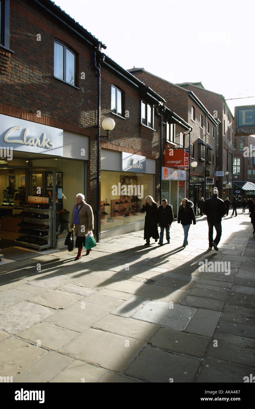 Early morning sun casts long shadows as people walk through Coppergate ...