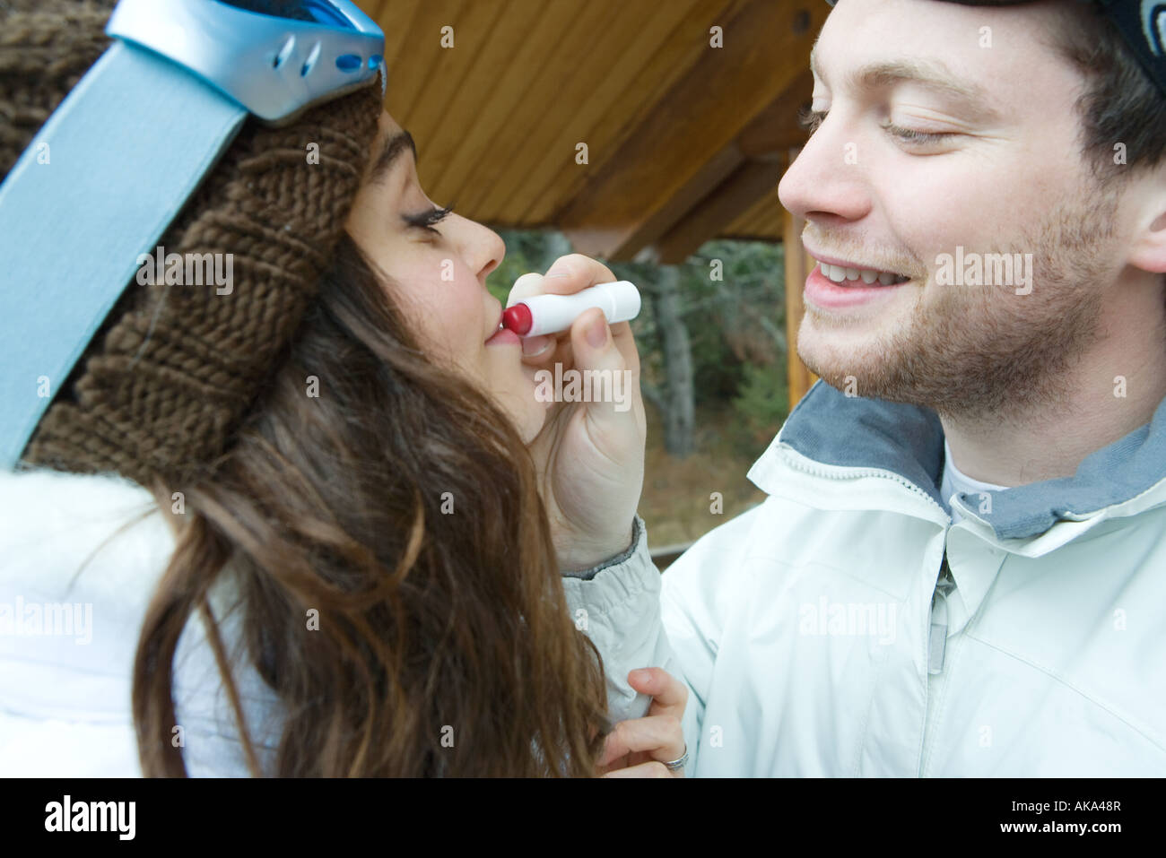 Young man applying lipstick to girlfriend's lips, side view Stock Photo ...