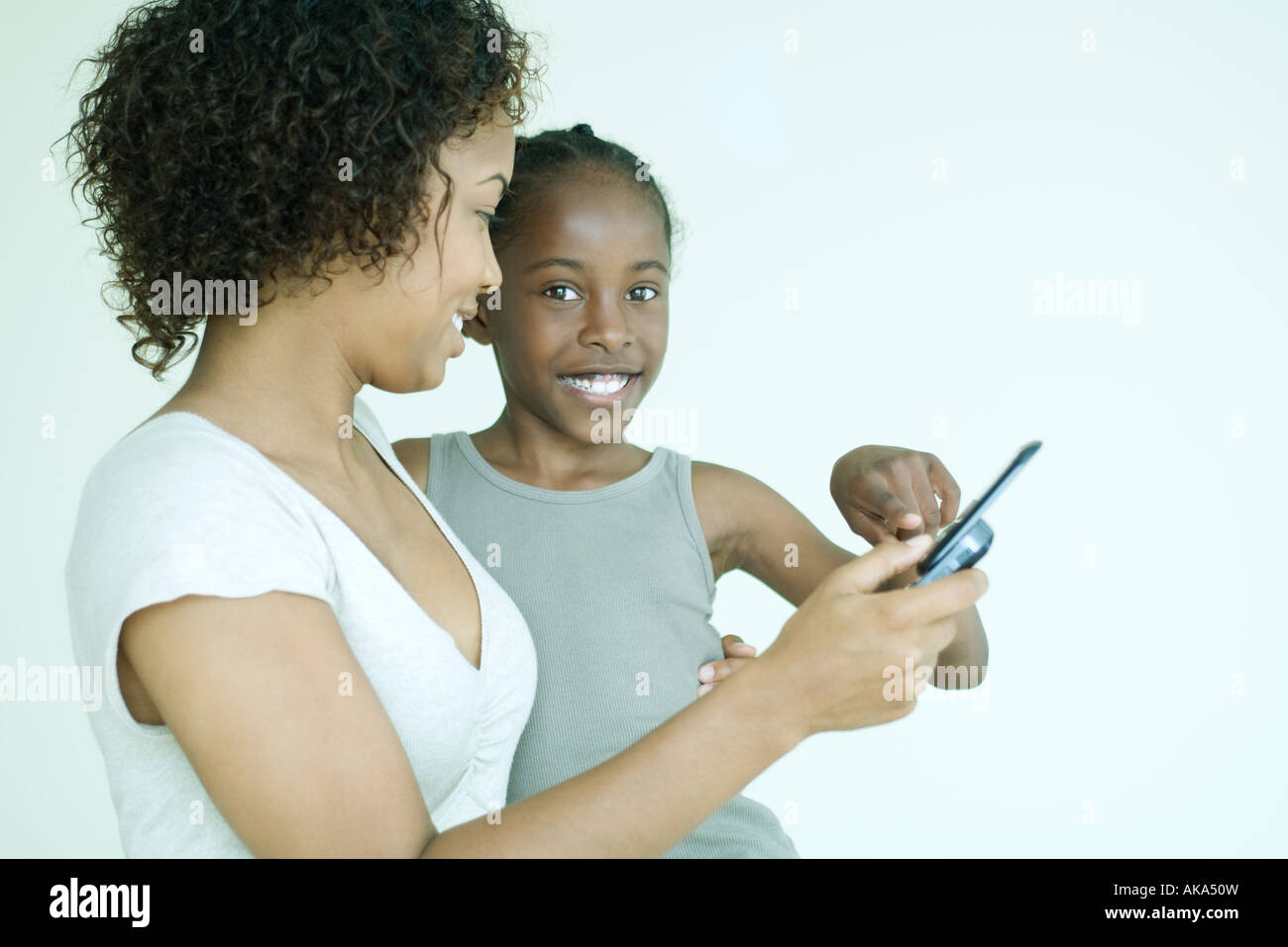 Mother showing daughter cell phone, daughter smiling at camera Stock ...