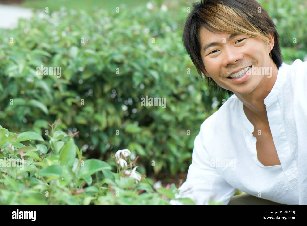 Man smiling at camera next to flowering shrub, portrait Stock Photo - Alamy