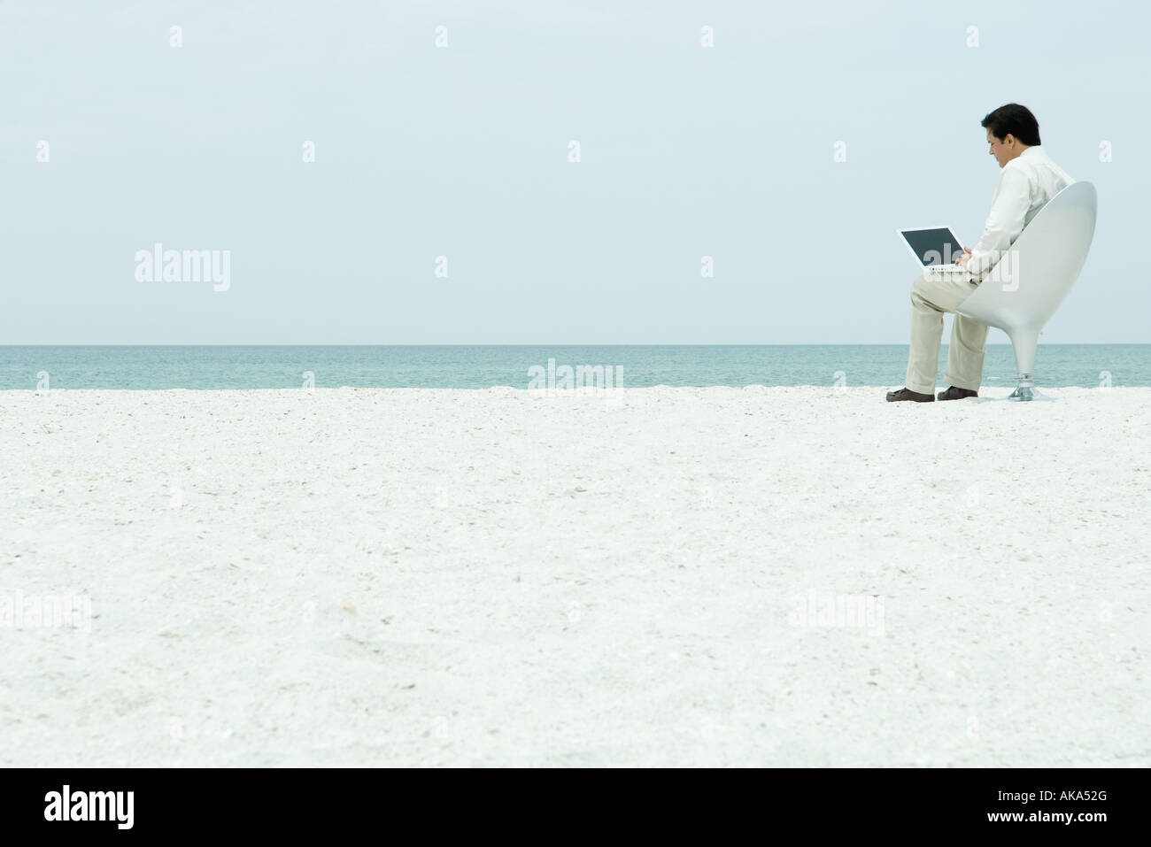 Man using laptop computer at the beach, full length Stock Photo - Alamy
