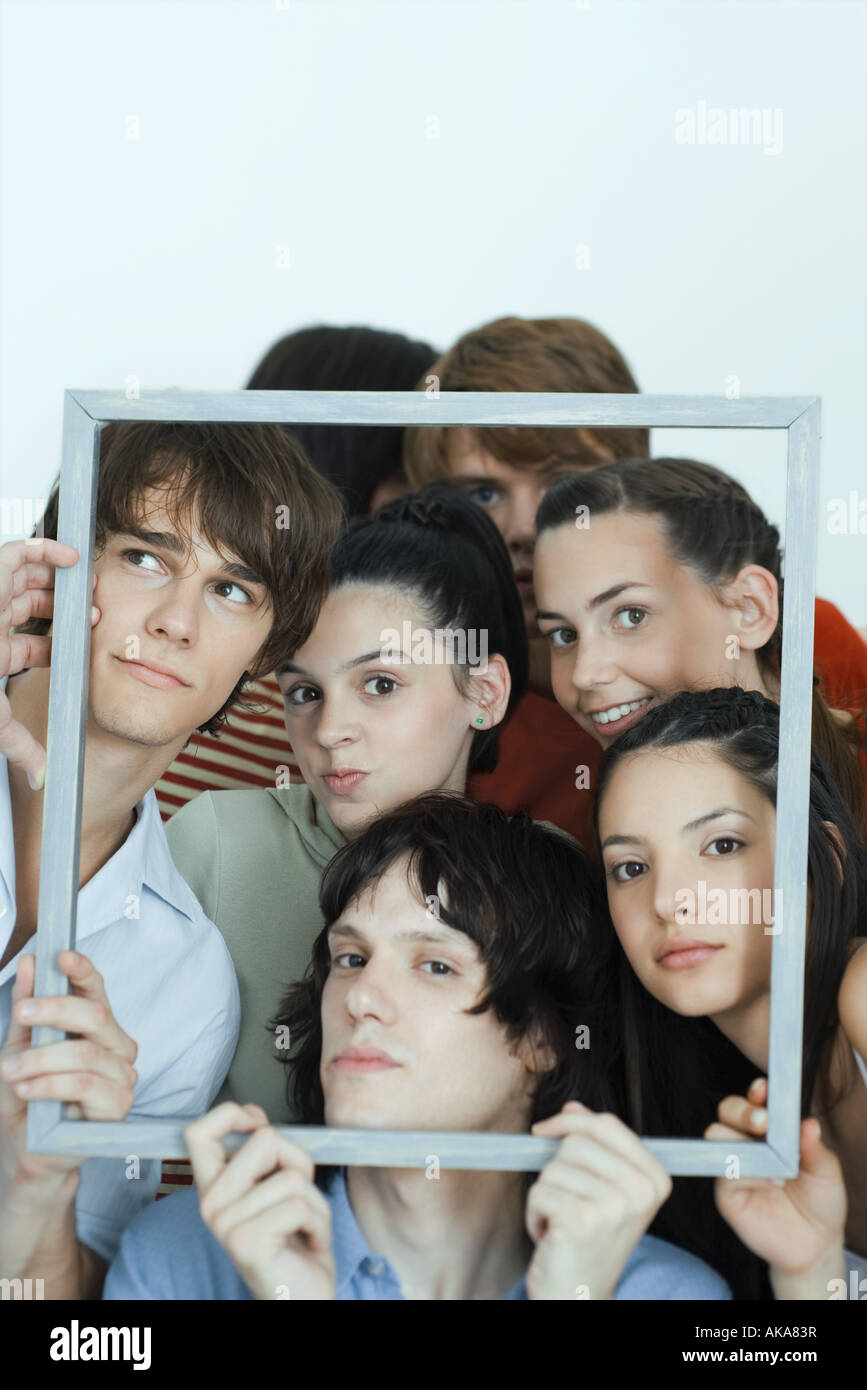 Group of young friends posing for photo, holding up picture frame ...