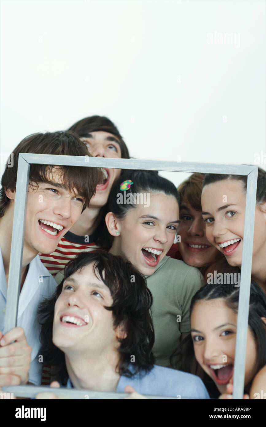 Group of young friends posing for photo, holding up picture frame ...