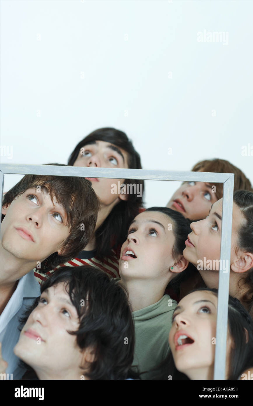 Group of young friends holding up picture frame, looking up, portrait ...