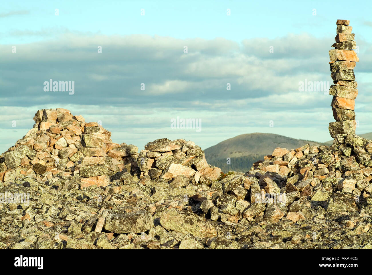 landscape with stones piled into a tower on the top of stony fell ...