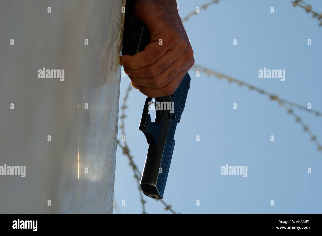 Hand holding pistol over barbed wires Stock Photo - Alamy
