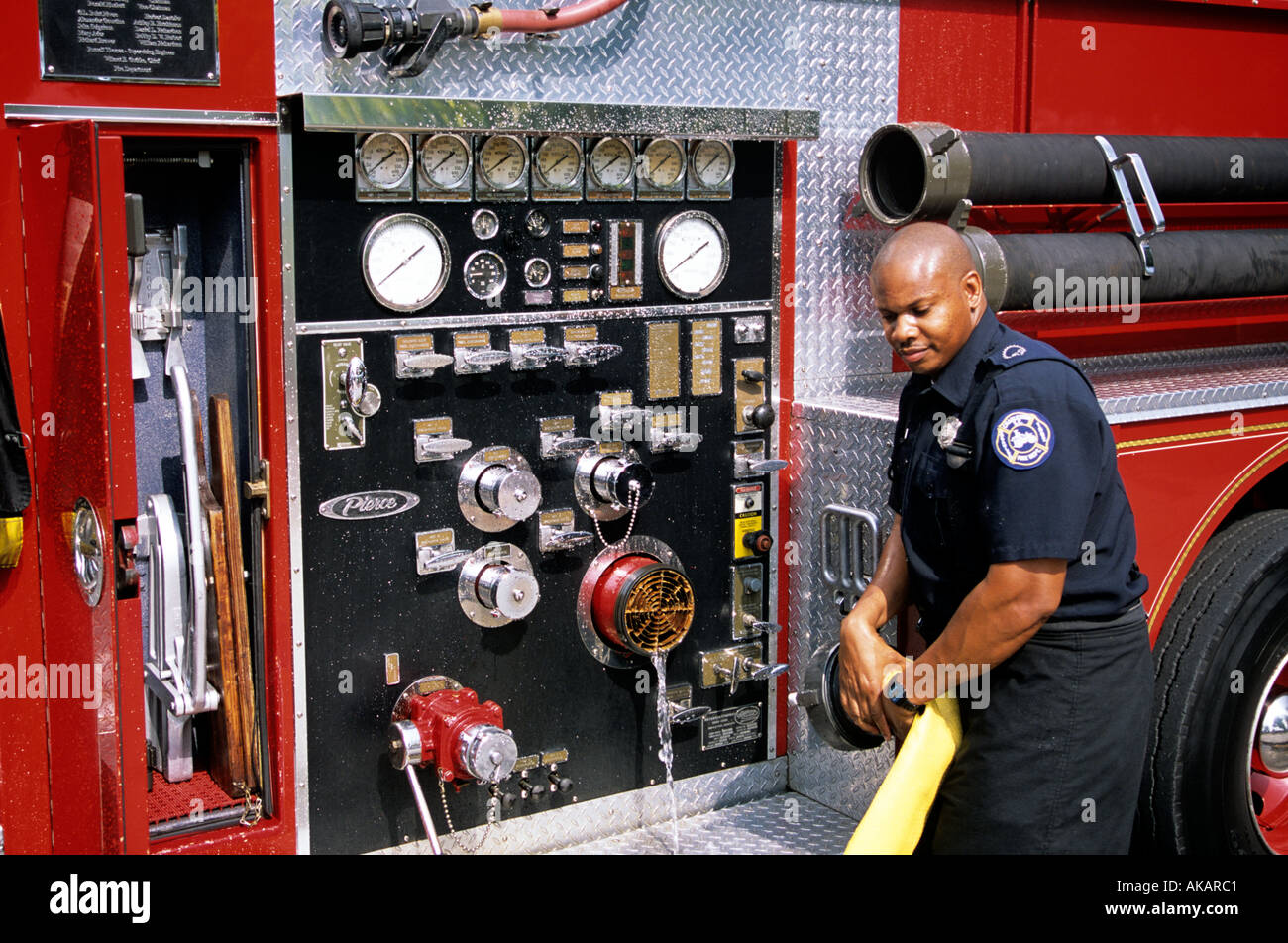 Fire fighter rolling up hoses by a fire engine USA Stock Photo - Alamy