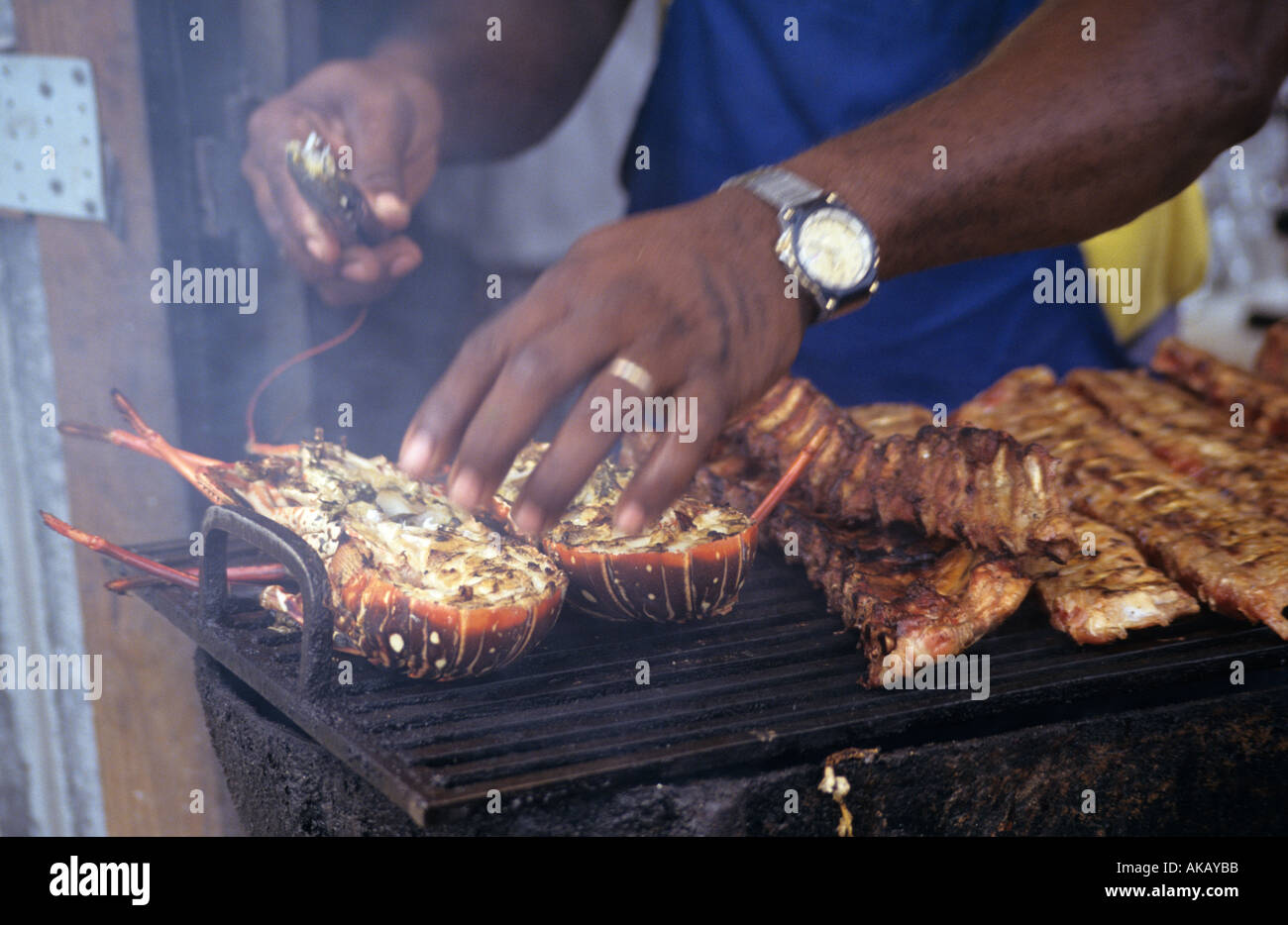Lobster being cooked on a Barbecue with cooks arms and smoke in ...