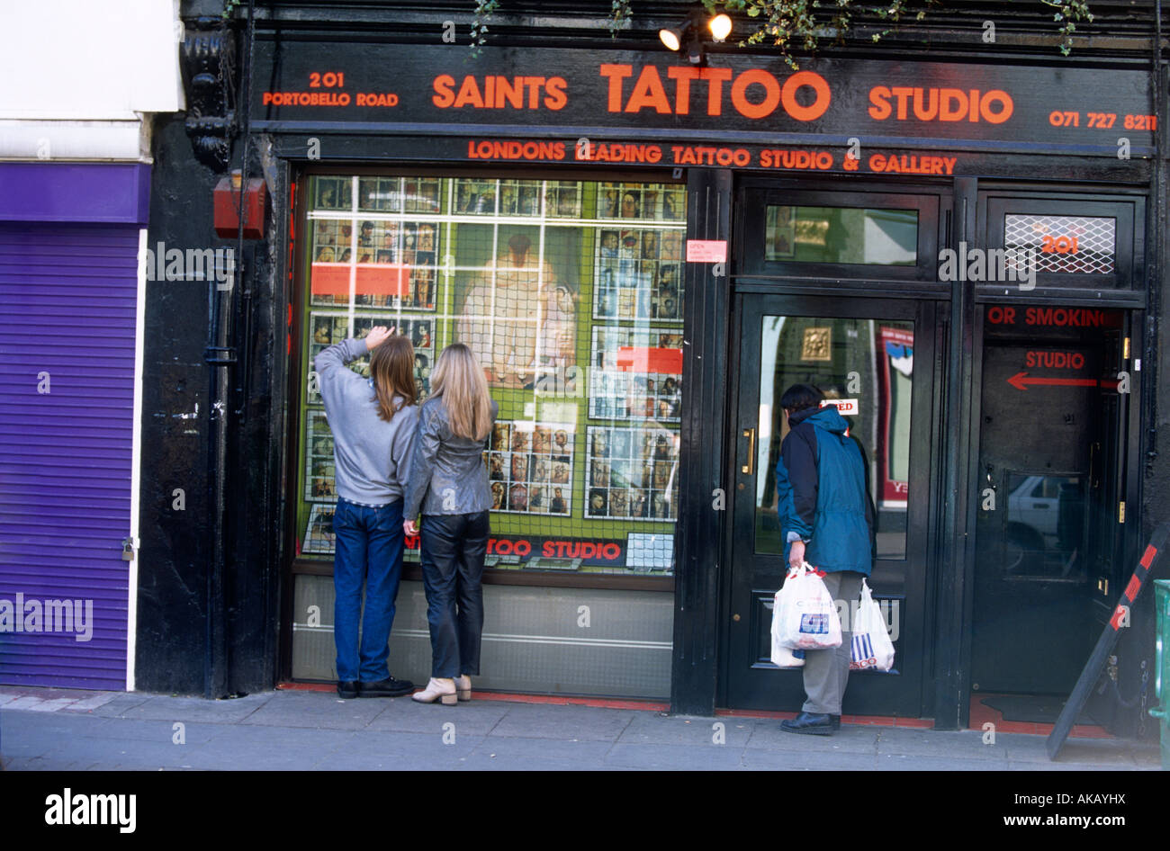 Passers-by look in tattoo shop window Stock Photo - Alamy