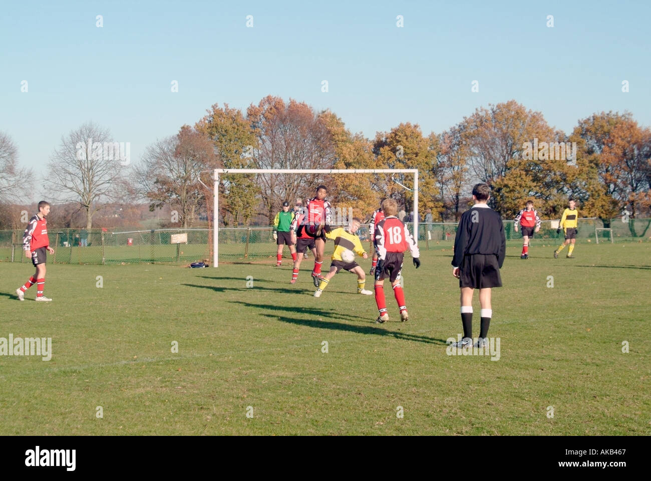 Football match in progress on village green pitch back view of referee ...
