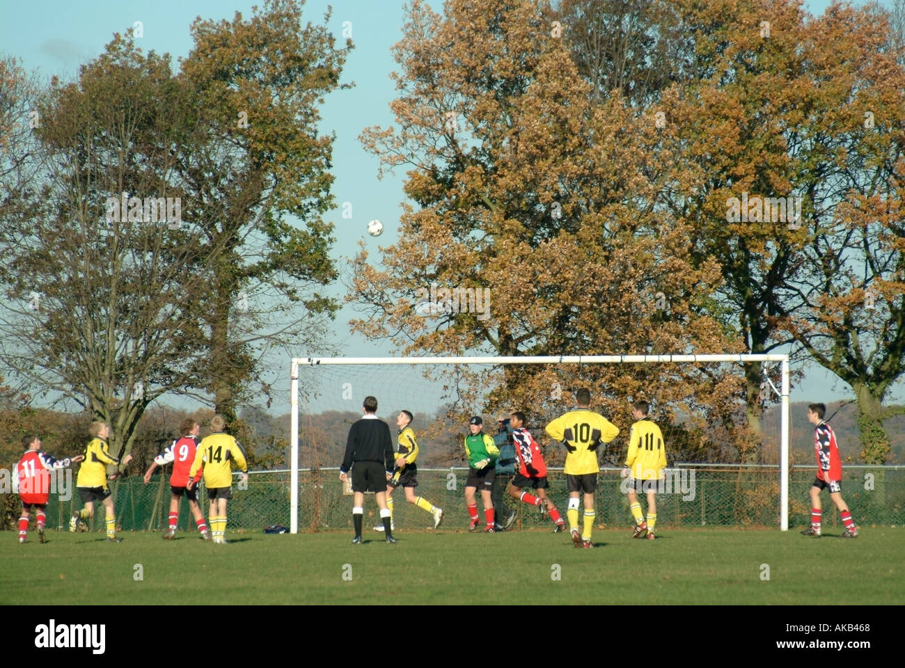 Football match in progress on village green pitch back view of referee ...