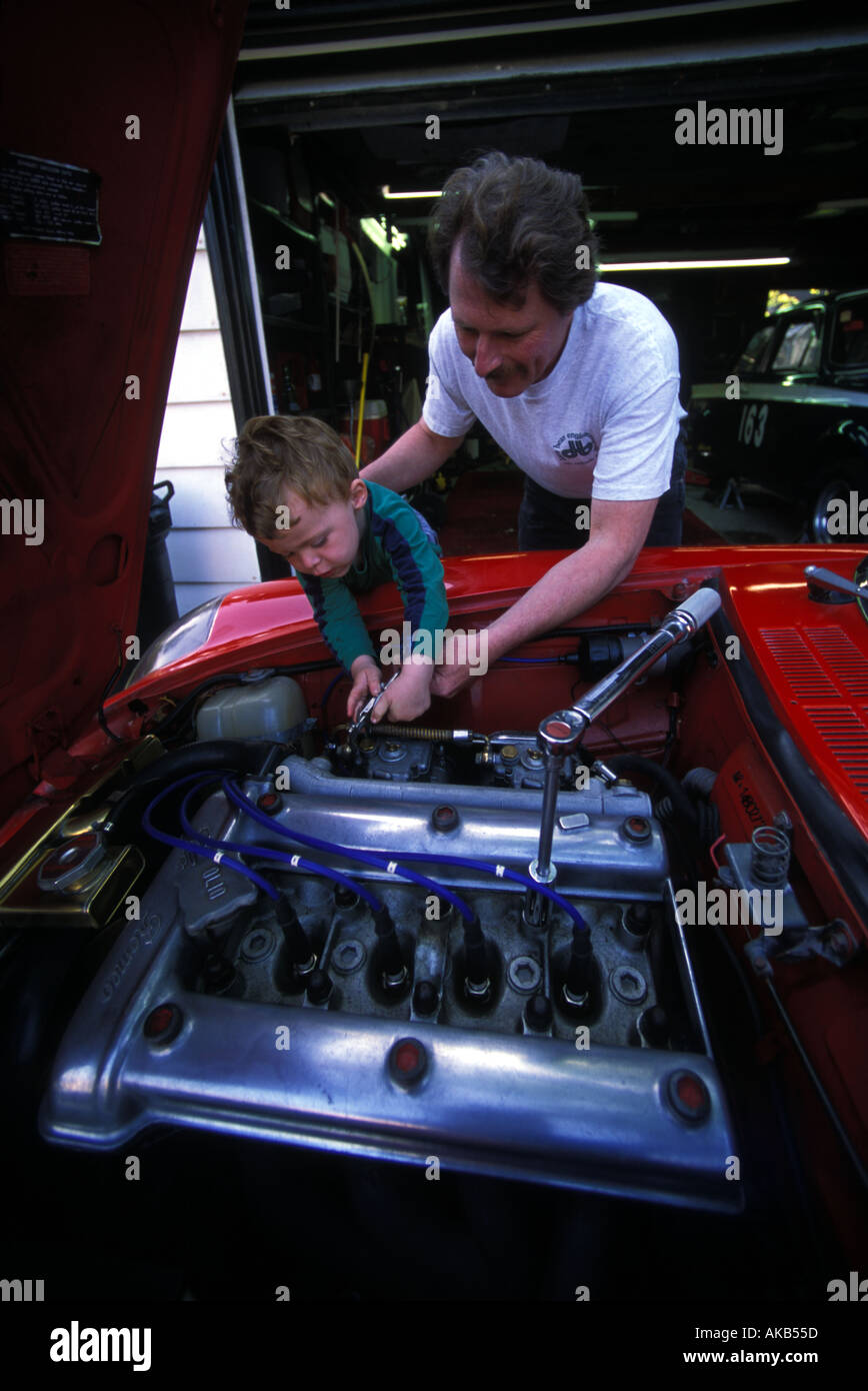 A father teaches his toddler son the mechanics of a car engine and tune ...