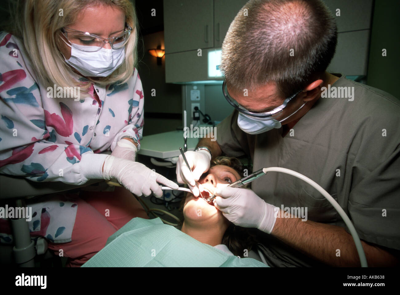 As a female patient reclines with mouth open wide a professional ...