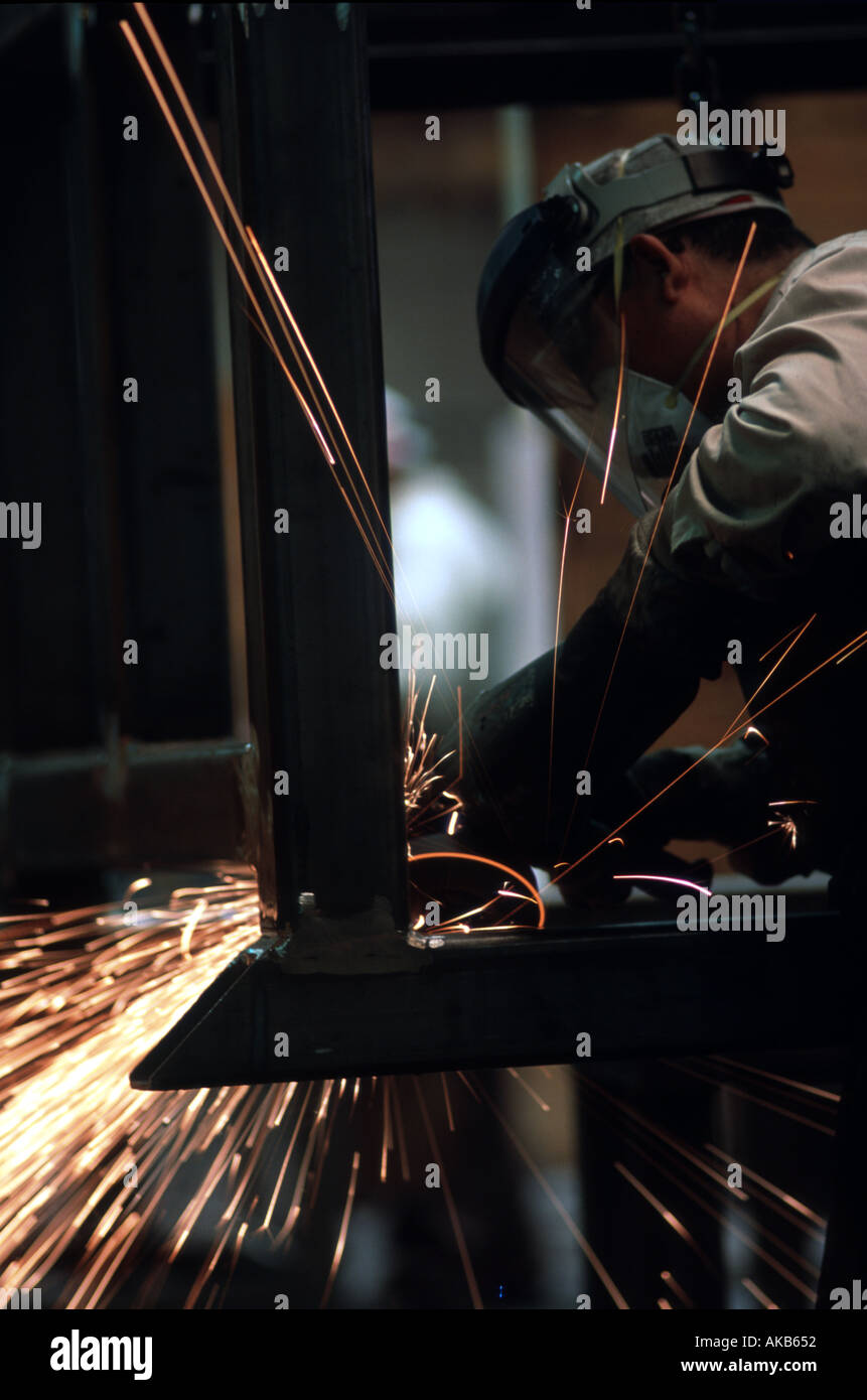 A skilled craftsman welding at his work bench is profiled with bright ...