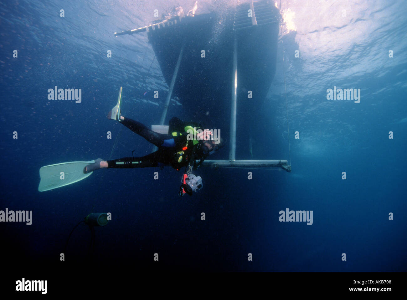 A scuba diver makes a safety stop on a hang bar at fifteen feet beneath ...