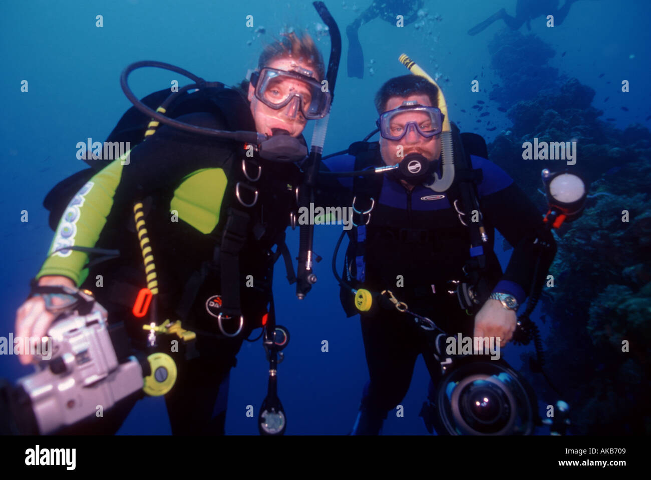 As buddies a male and female scuba diver pose together as they carry ...
